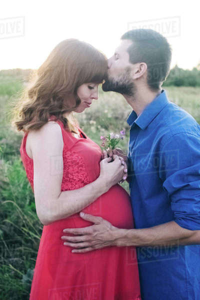 A married couple who are expecting a baby are photographed at sunset in ...