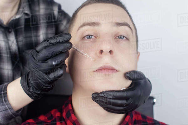 Beard growth. The master in the barber shop applies a special oil to ...