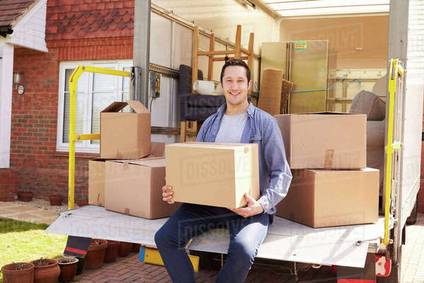 Man unpacking moving in boxes from removal truck - Stock Photo - Dissolve