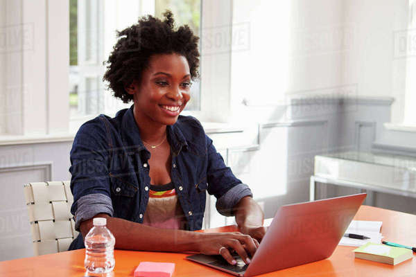 Young black woman using laptop computer at a desk, close-up - Stock ...