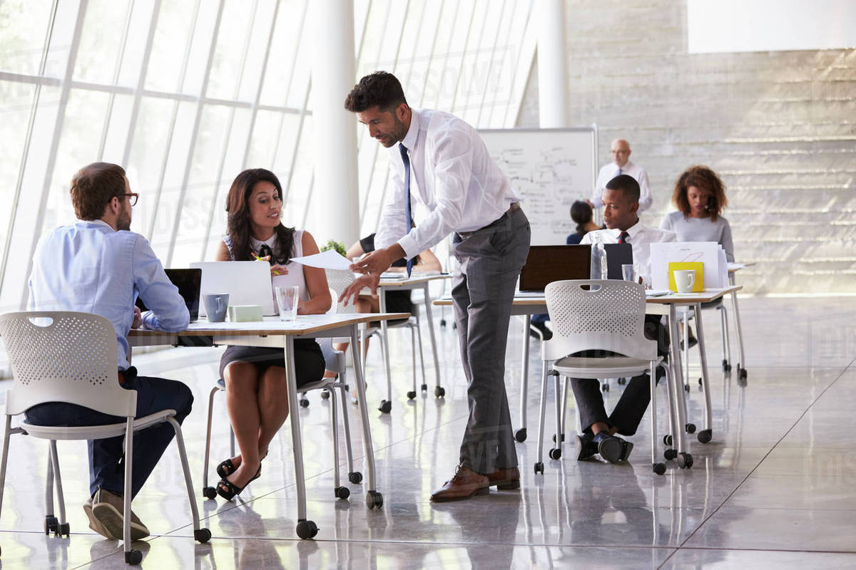 Manager helping staff in busy office environment - Royalty-free Stock ...