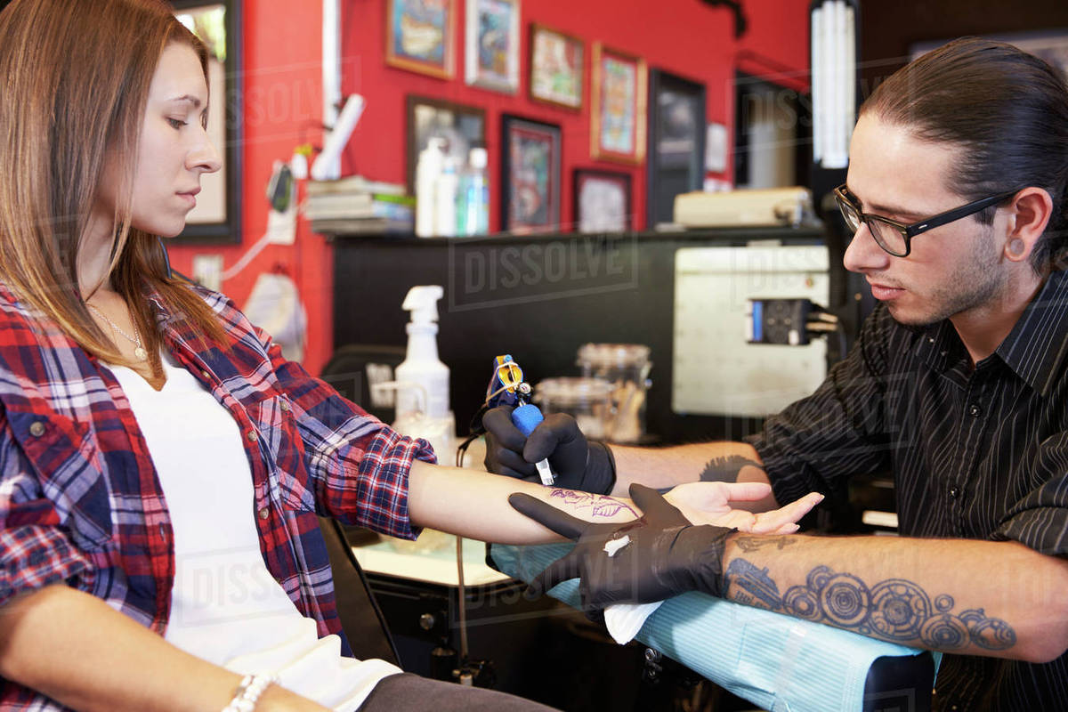 Woman sitting in chair having tattoo on arm in parlor - Royalty-free ...