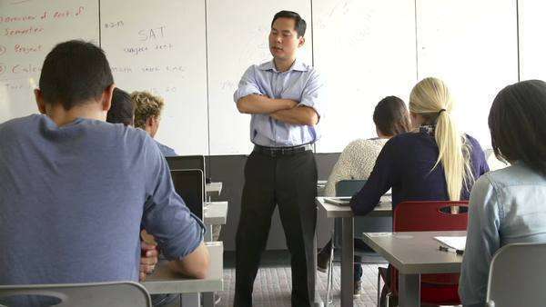 View from back of class using laptops to teacher standing at whiteboard ...
