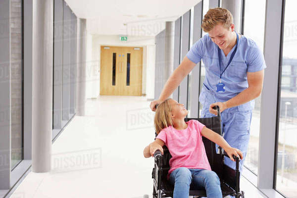 Nurse Pushing Girl In Wheelchair Along Corridor - Stock Photo - Dissolve