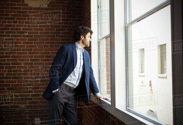 Businessman standing by office window - Stock Photo - Dissolve
