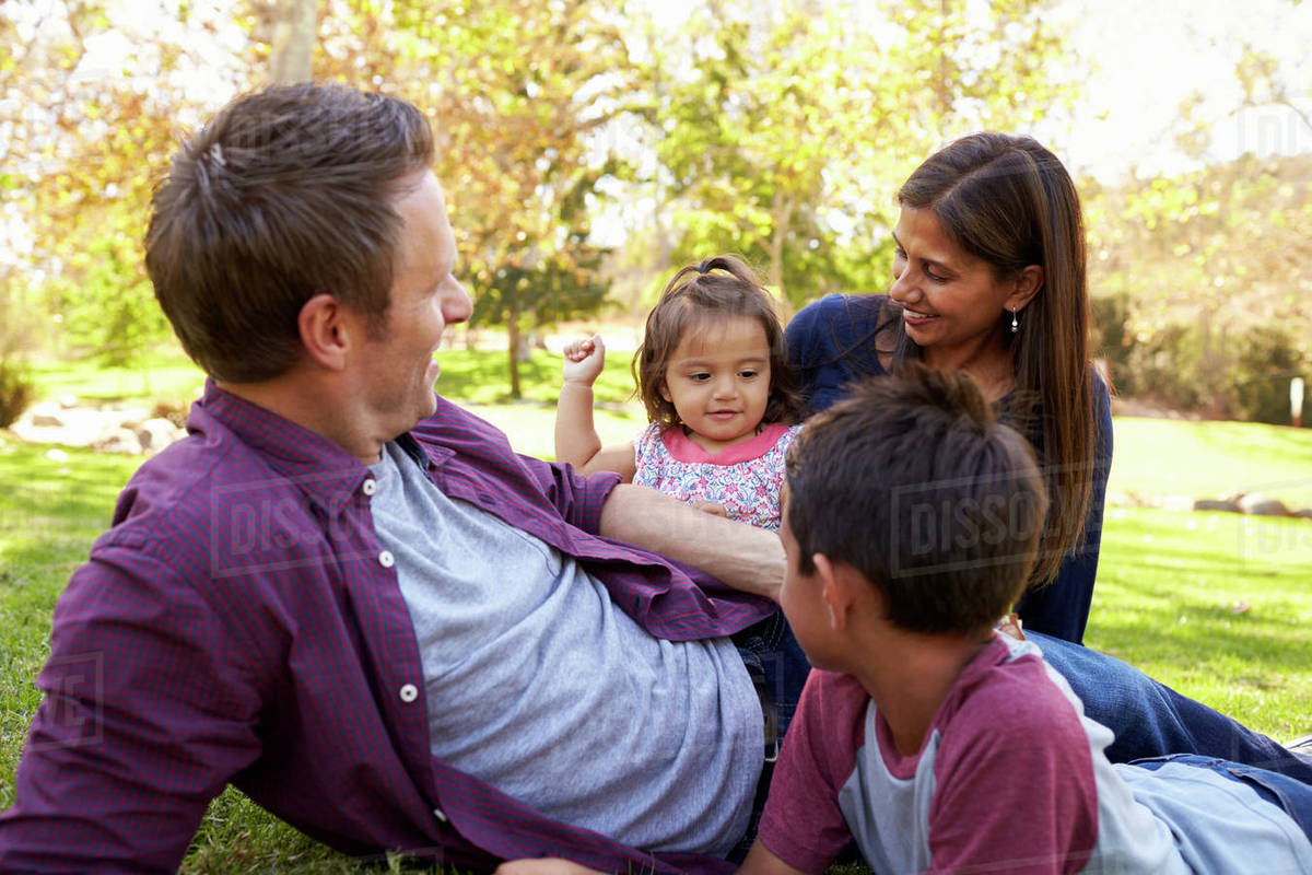 Young mixed race family relaxing together in a park - Royalty-free ...
