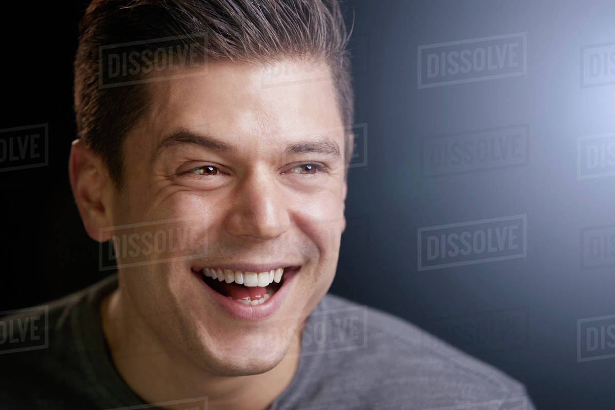 Portrait of a smiling young white man on black background - Royalty ...