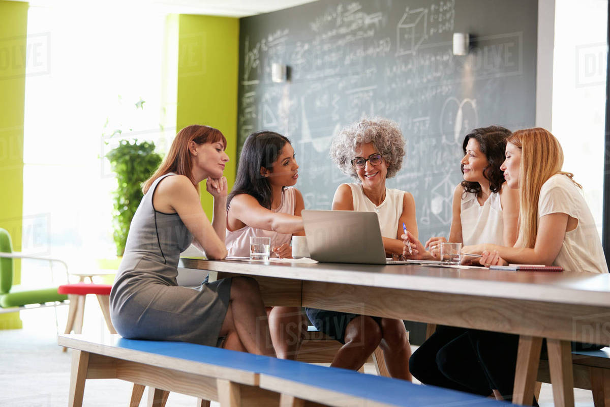 Female work colleagues using laptop in an informal meeting - Royalty ...