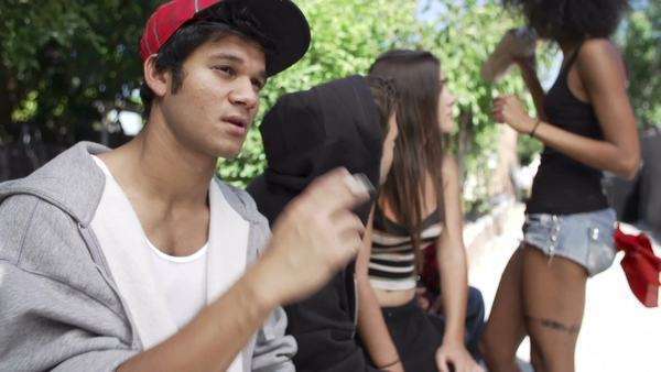 Slow motion sequence of gang of young people on street corner smoking ...