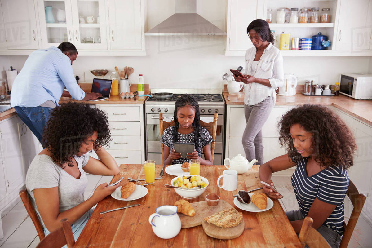 Family Sitting Around Breakfast Table Using Digital Devices Stock Photo Dissolve