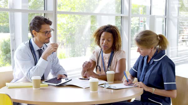 Medical team having meeting sitting around table in hospital - 4K ...