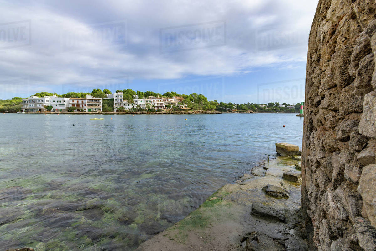 Quiet waterside view of a coastal town with a foreground of stone walls ...