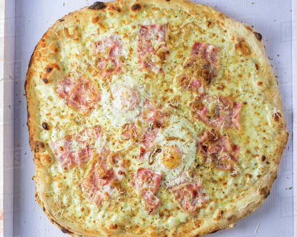 Fresh pizza carbonara with ham and scrambled egg on the concrete ...