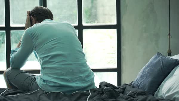 Sad, unhappy man sitting on edge of bed at home - Stock Video Footage ...