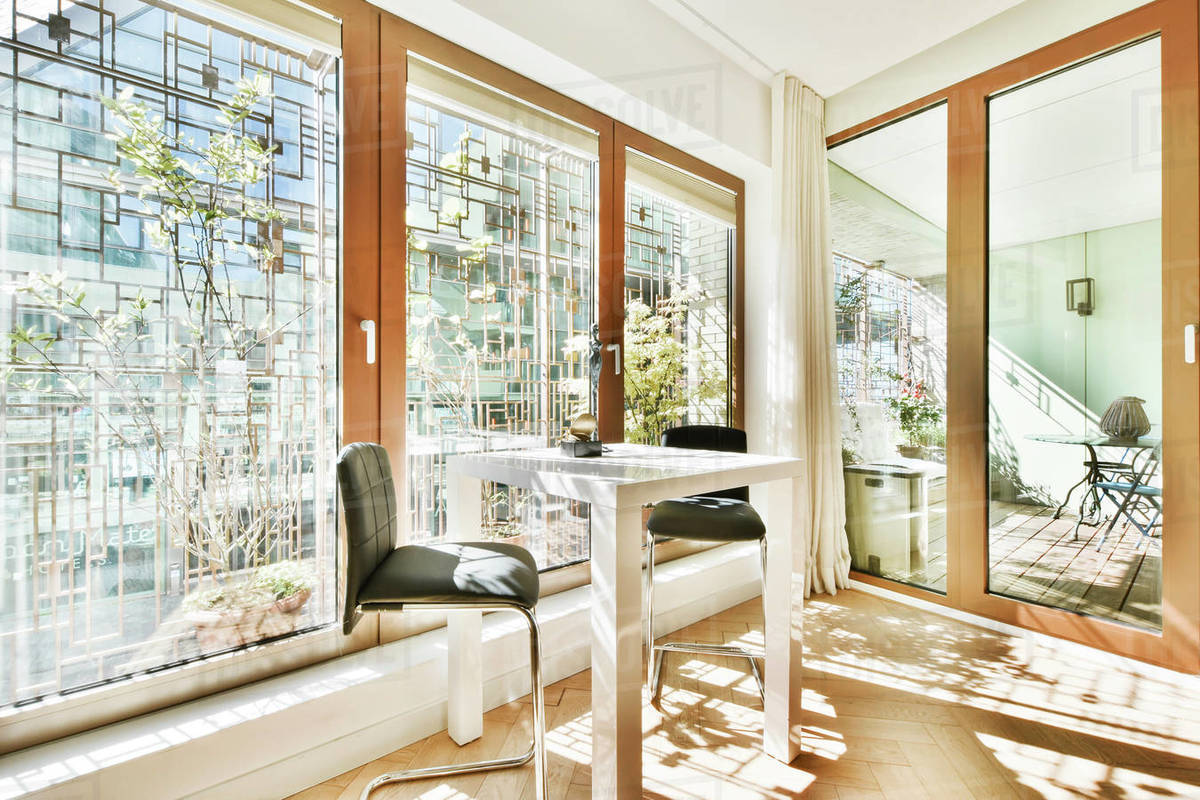 Sun lit room with small table and stools near panoramic window viewing ...