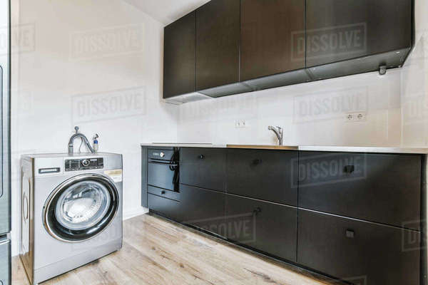 Black cupboards with stove and sink located near contemporary washing ...