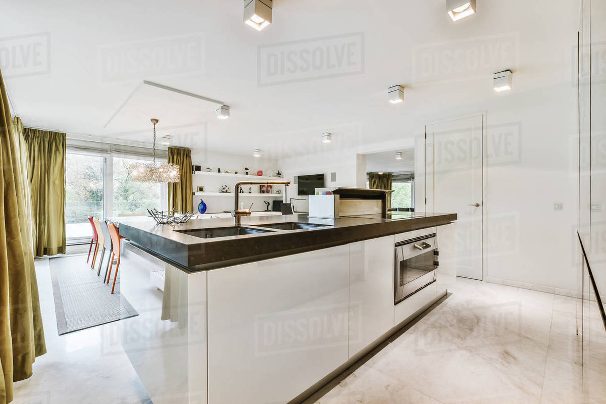 Big island counter with sink and built in appliance in white living ...