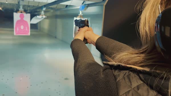 Woman shooting at a target with a pistol in a shooting range. Woman ...
