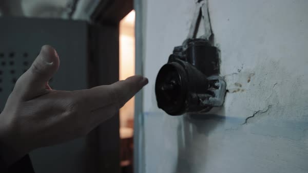 Old light switch. A man's hand in a dark room turns the light on and ...