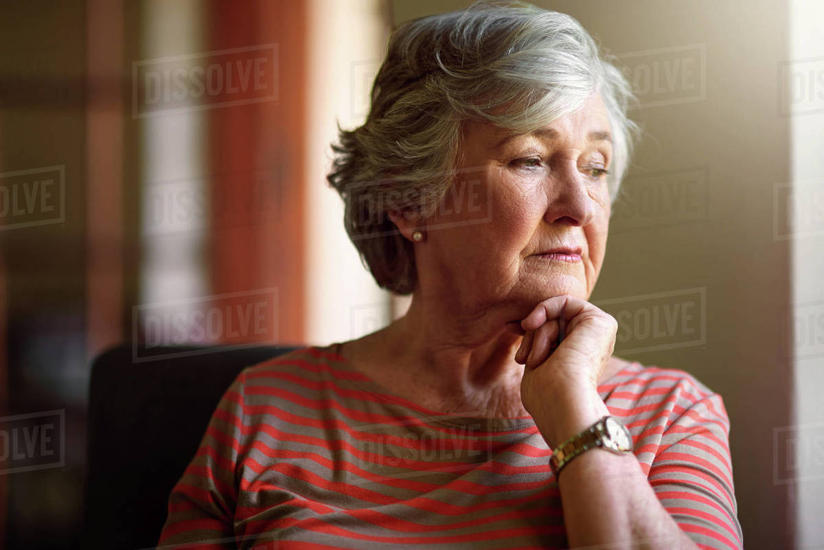 Senior woman, worry and thinking at window with memory, ideas and home on living room sofa ...