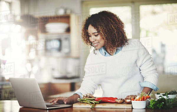 Happy woman following an online recipe, cooking healthy food on her ...