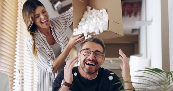 Homeowner, relocation and unpacking with a laughing couple playing ...