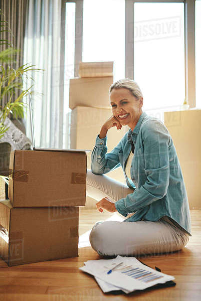 Woman, boxes and portrait with document on the floor with a smile at a ...