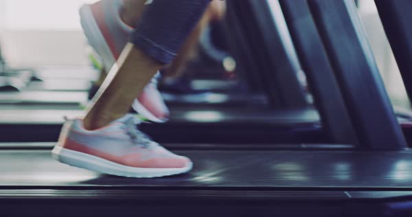 Feet running on a treadmill machine together as a group at an indoor ...