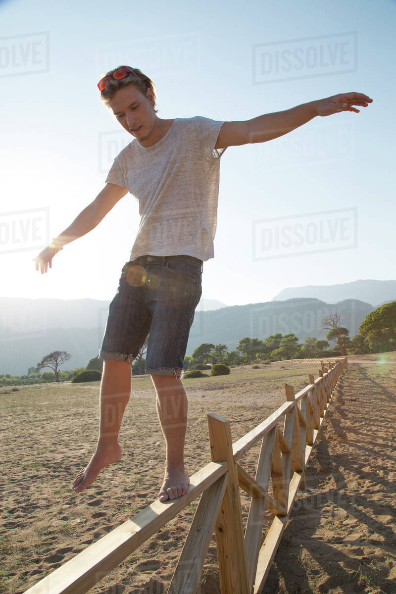 Man balancing on a wooden fence - Royalty-free Stock Photo | Dissolve