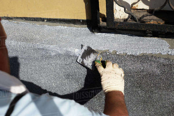 Man levels special solution for building restoration on wall using ...