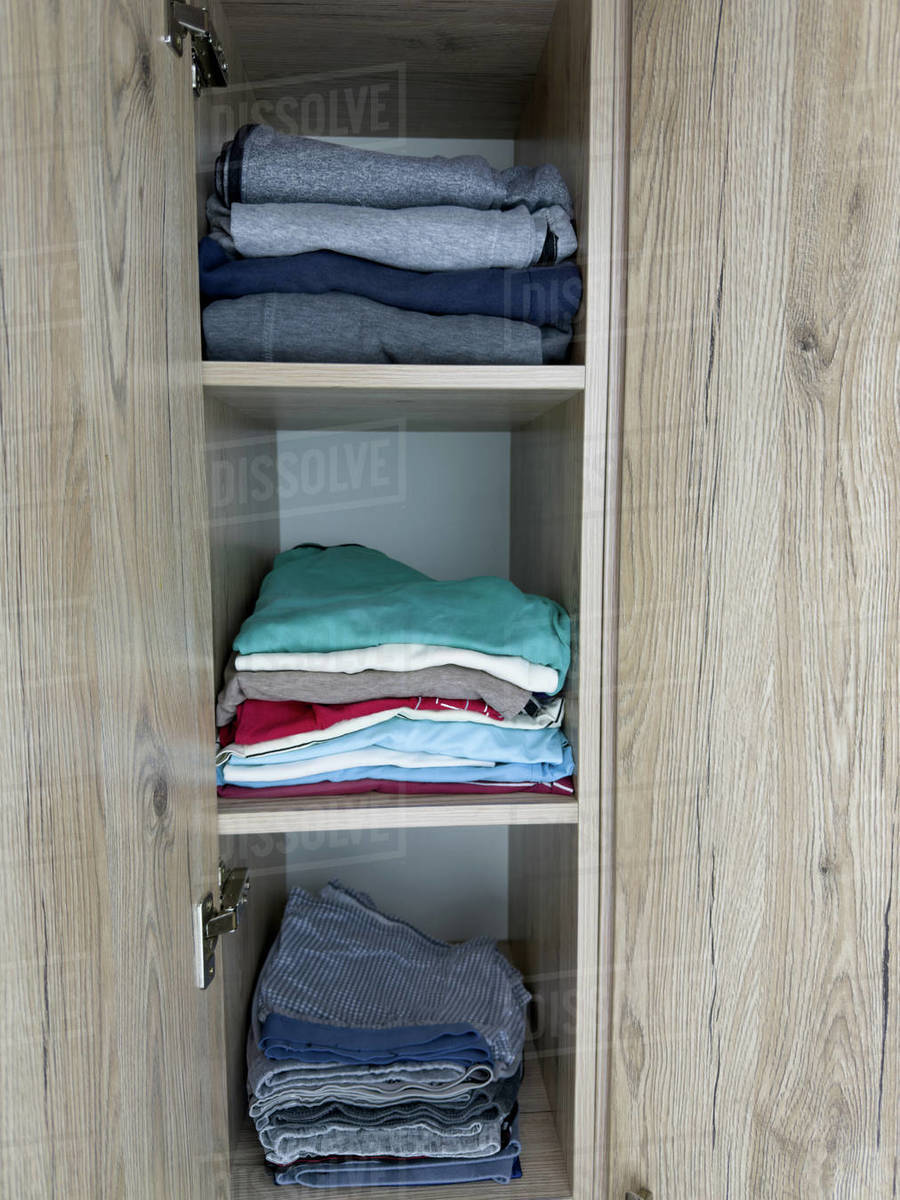 Vertical photo of closet shelves with home clean clothes in wooden ...