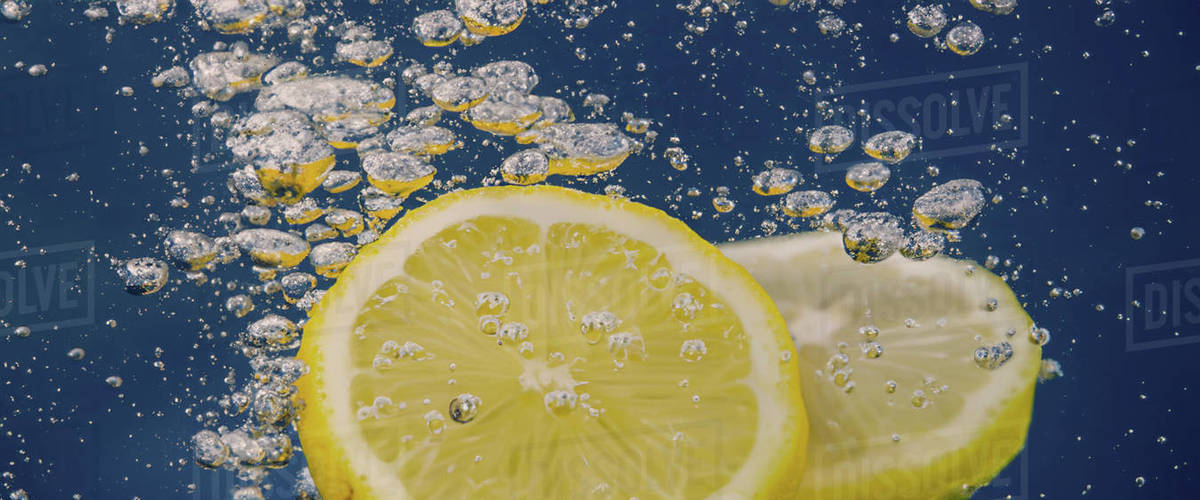Underwater lemon slice in soda water or lemonade with bubbles. Refreshing soda tonic fizzy ...