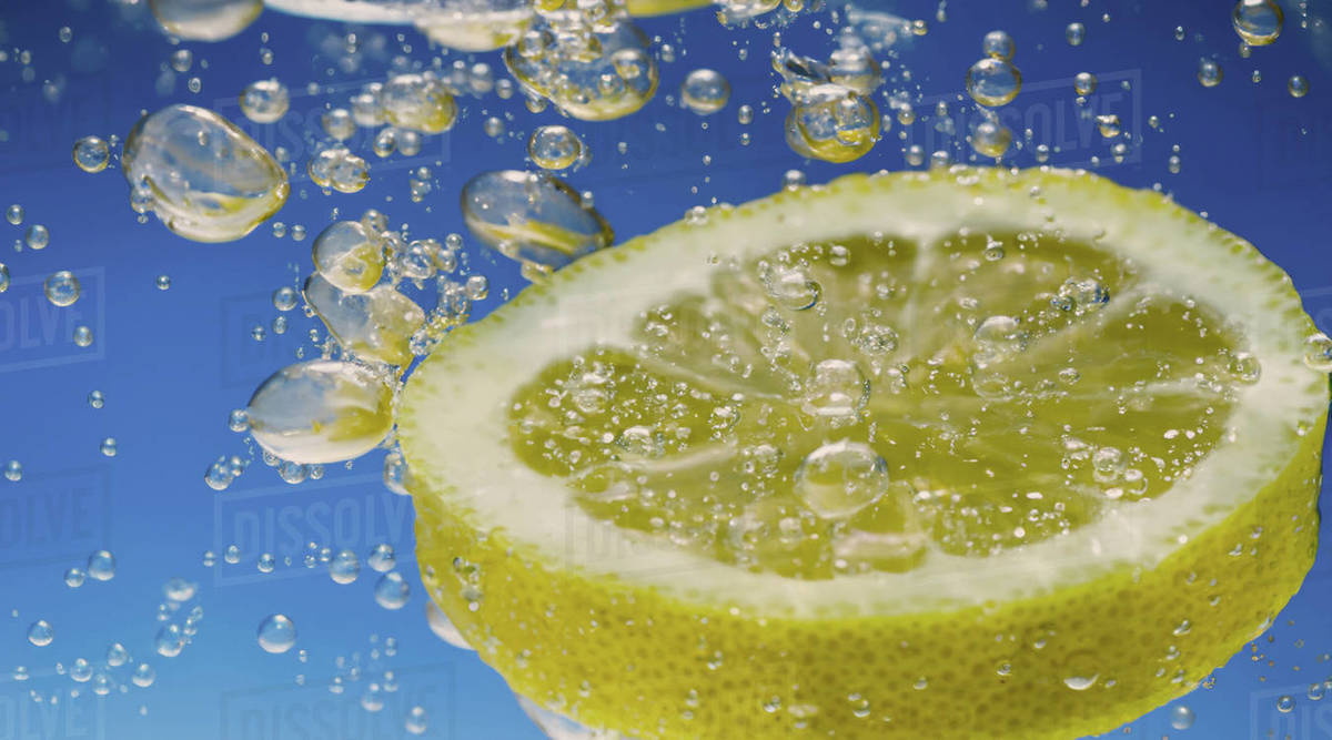 Underwater lemon slice in soda water or lemonade with bubbles. Refreshing soda tonic fizzy ...