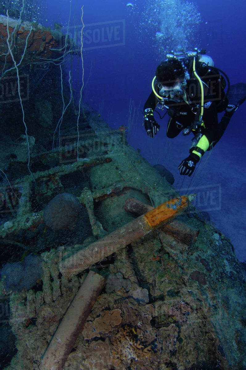 Scuba diver looks at live 5 inch shells on submarine wreck USS Apogon ...