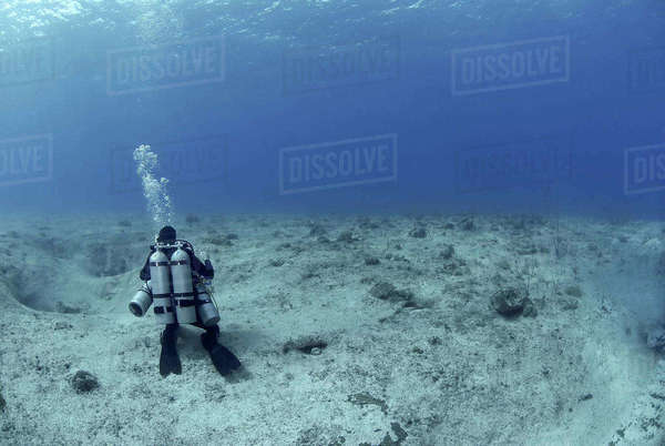 Technical scuba diver kneeling on barren bottom, Grand Cayman Island ...