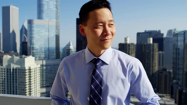 Asian American business manager on rooftop overlooking cityscape ...