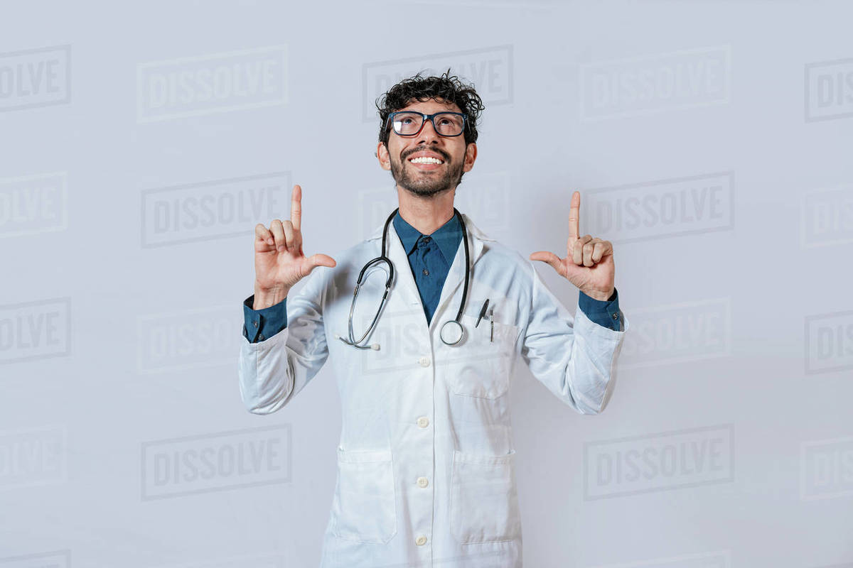 Handsome doctor pointing up. Smiling doctor pointing a promo up. Male ...