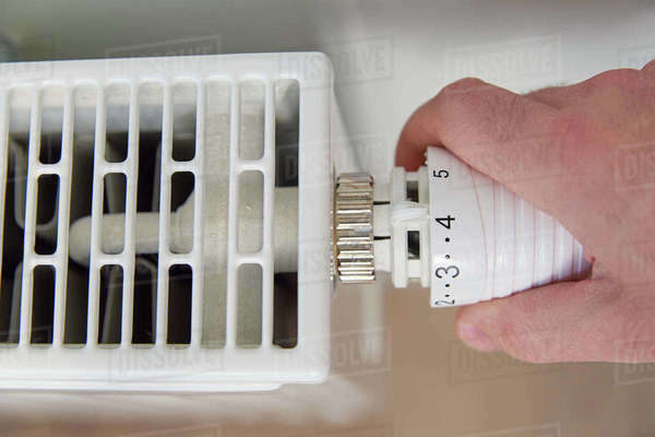 Hand adjusting temperature on heating radiator thermostat, Turning heat ...