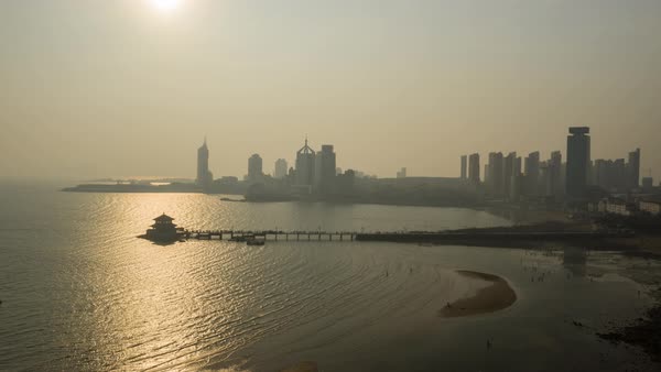 Sunset flight over qingdao city famous palace by the sea and bay pier ...