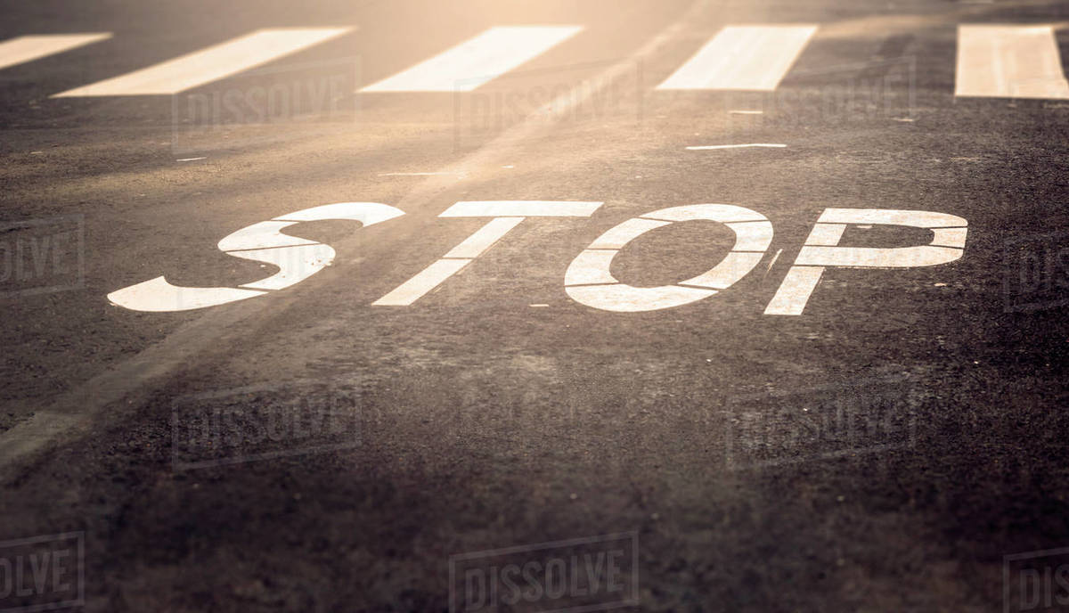 A stop sign painted on the road with crosswalk in the distance - Stock ...
