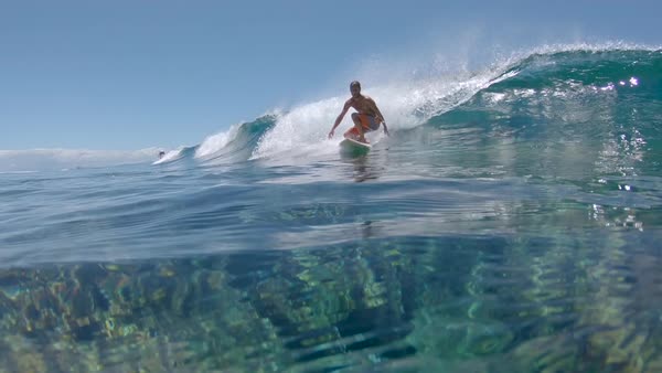 Extreme surfer does a cool hand drag while riding a big tube wave ...