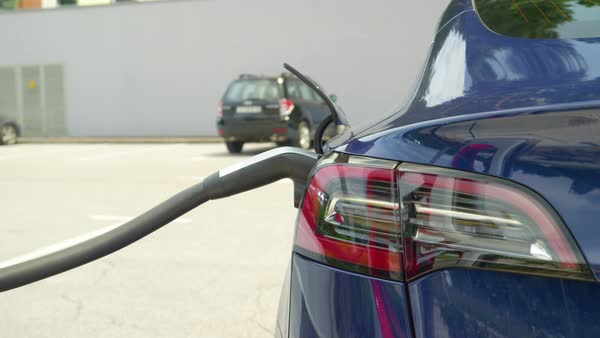CLOSE UP: Detailed shot of a shiny new Tesla car recharging at a ...
