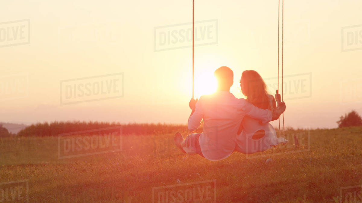 Happy young couple playfully grinning and looking over their shoulders ...