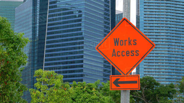 CLOSE UP Works access sign in front of tall glassy skyscrapers in ...