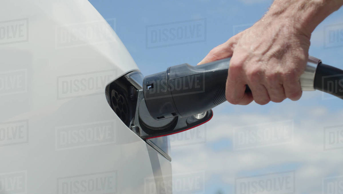 CLOSE UP, LOW ANGLE VIEW: Man plugging in electric car at charging ...