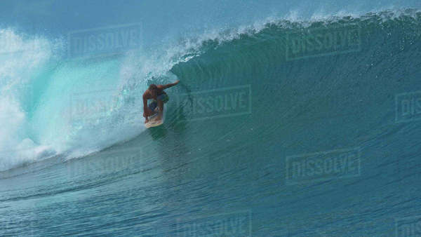 CLOSE UP: Male surfboarder drags his hand behind him through the ...