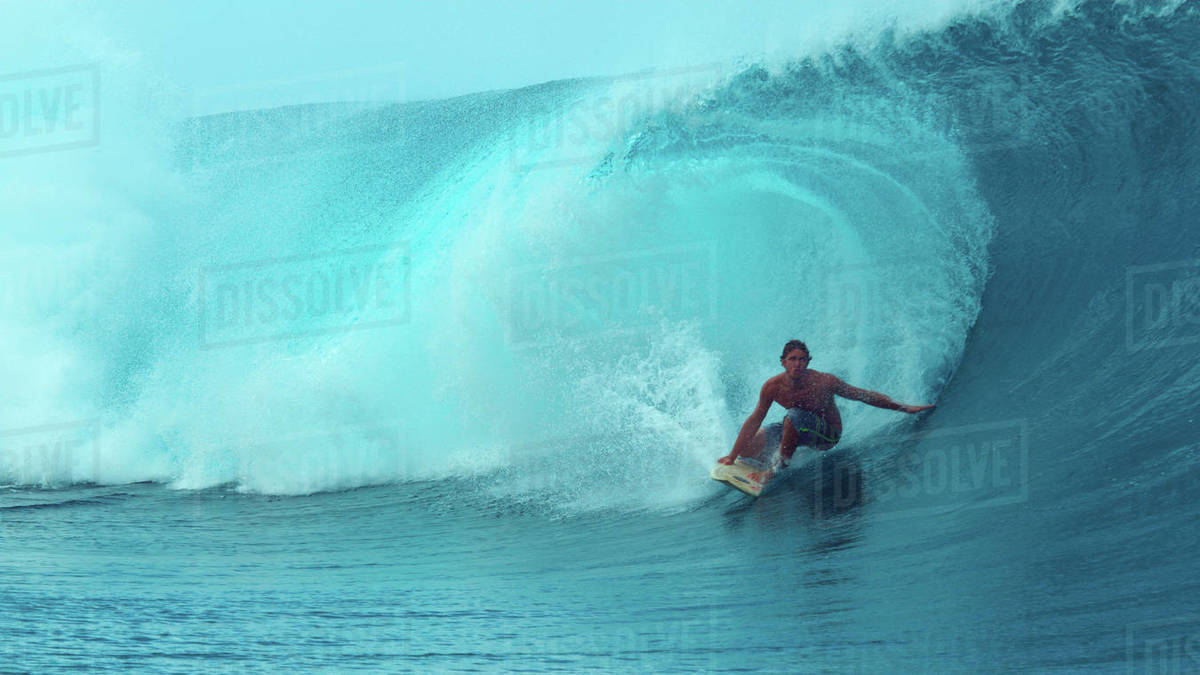 CLOSE UP: Pro surfer riding a big wave drags his hand through the ...