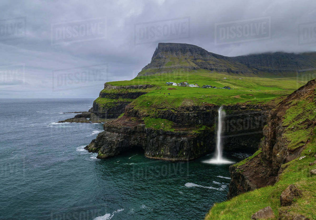 AERIAL: Picturesque village under grassy mountains and the spectacular ...