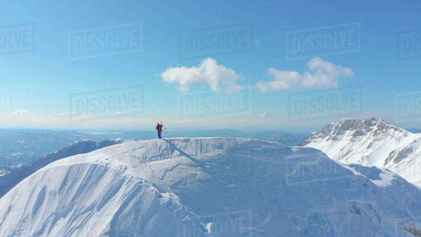 AERIAL: Unrecognizable skier taking photos after reaching the high peak ...