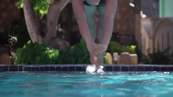 Happy young woman jumping headfirst into swimming pool on the garden at ...